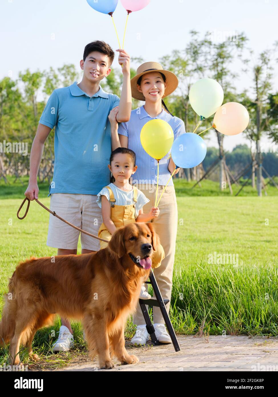 Happy family of three and pet dog in the park smiling Stock Photo - Alamy