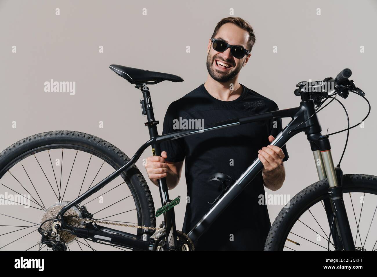 Excited young rider man smiling while posing with his bicycle isolated ...