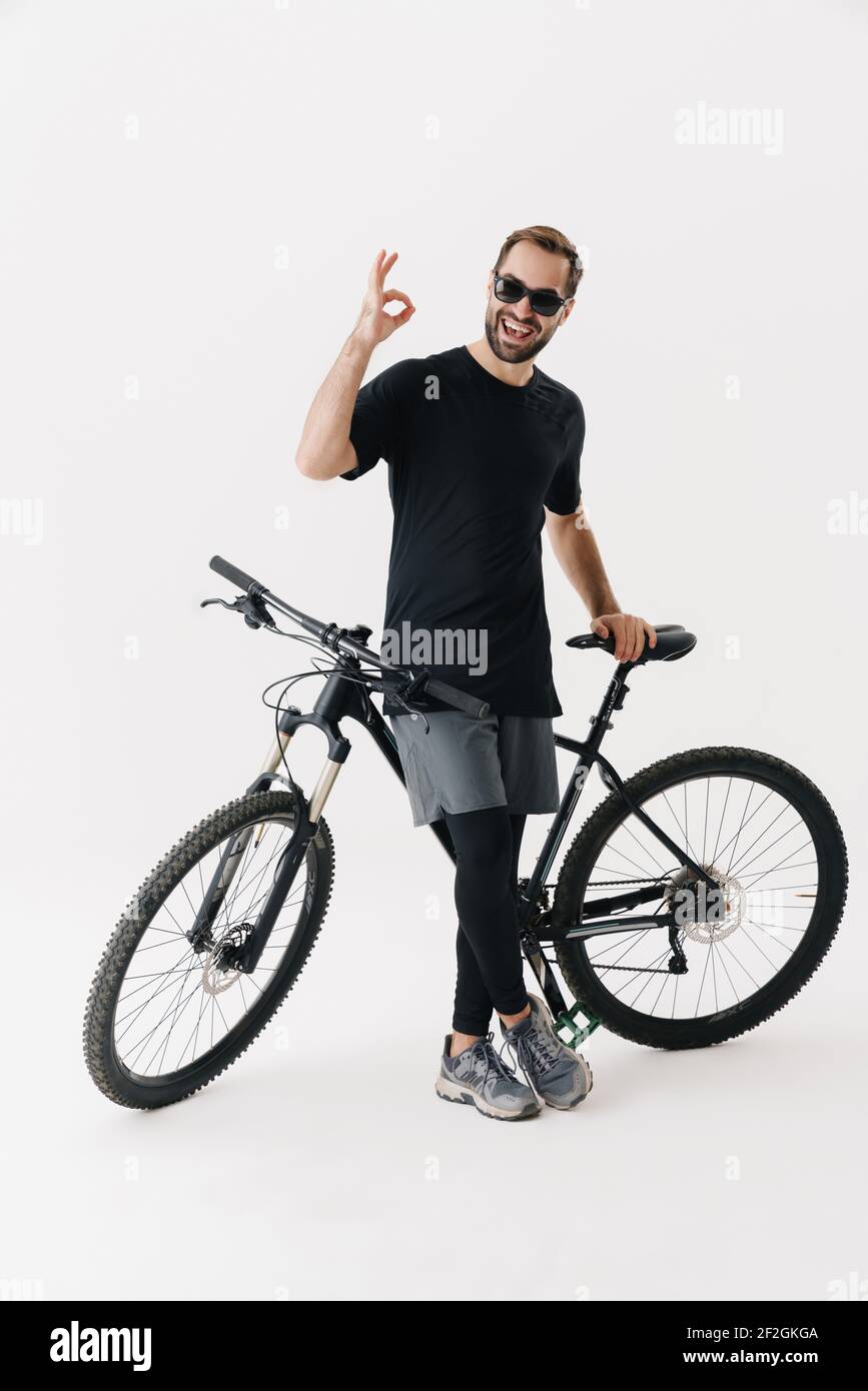 Happy rider man showing ok sign while posing with his bicycle isolated ...