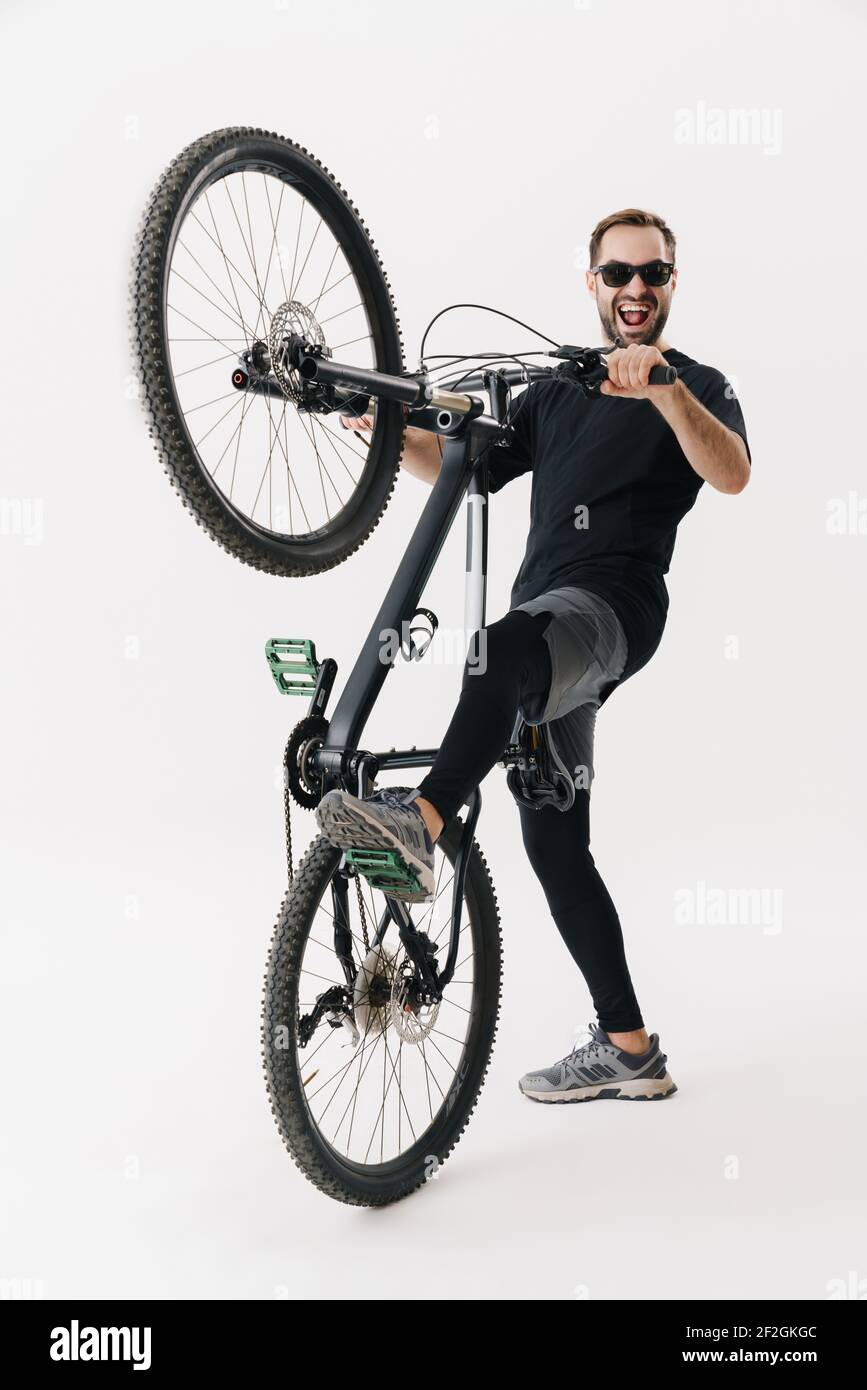 Excited young rider man smiling while posing with his bicycle isolated ...