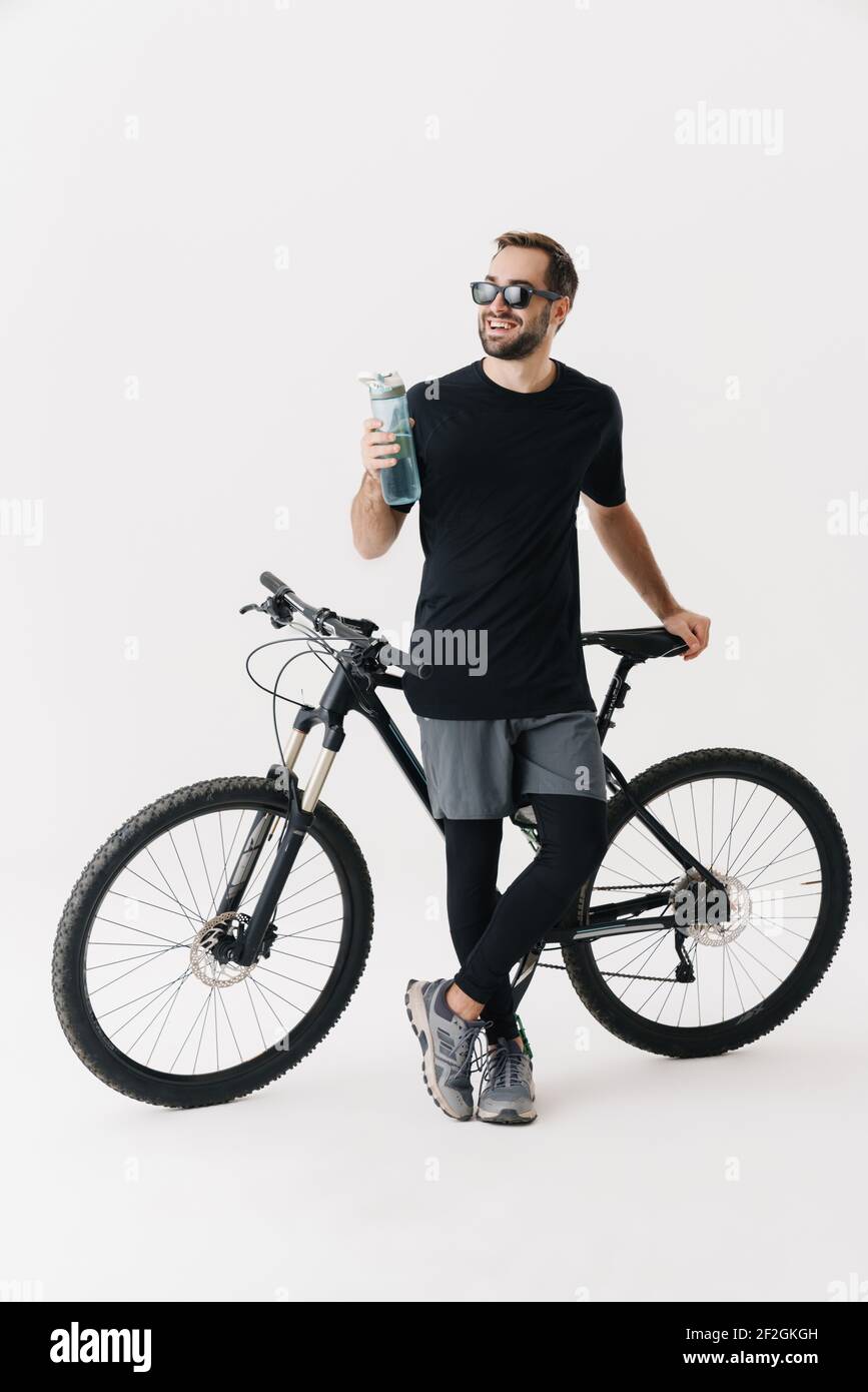 Happy rider man drinking water while posing with his bicycle isolated ...