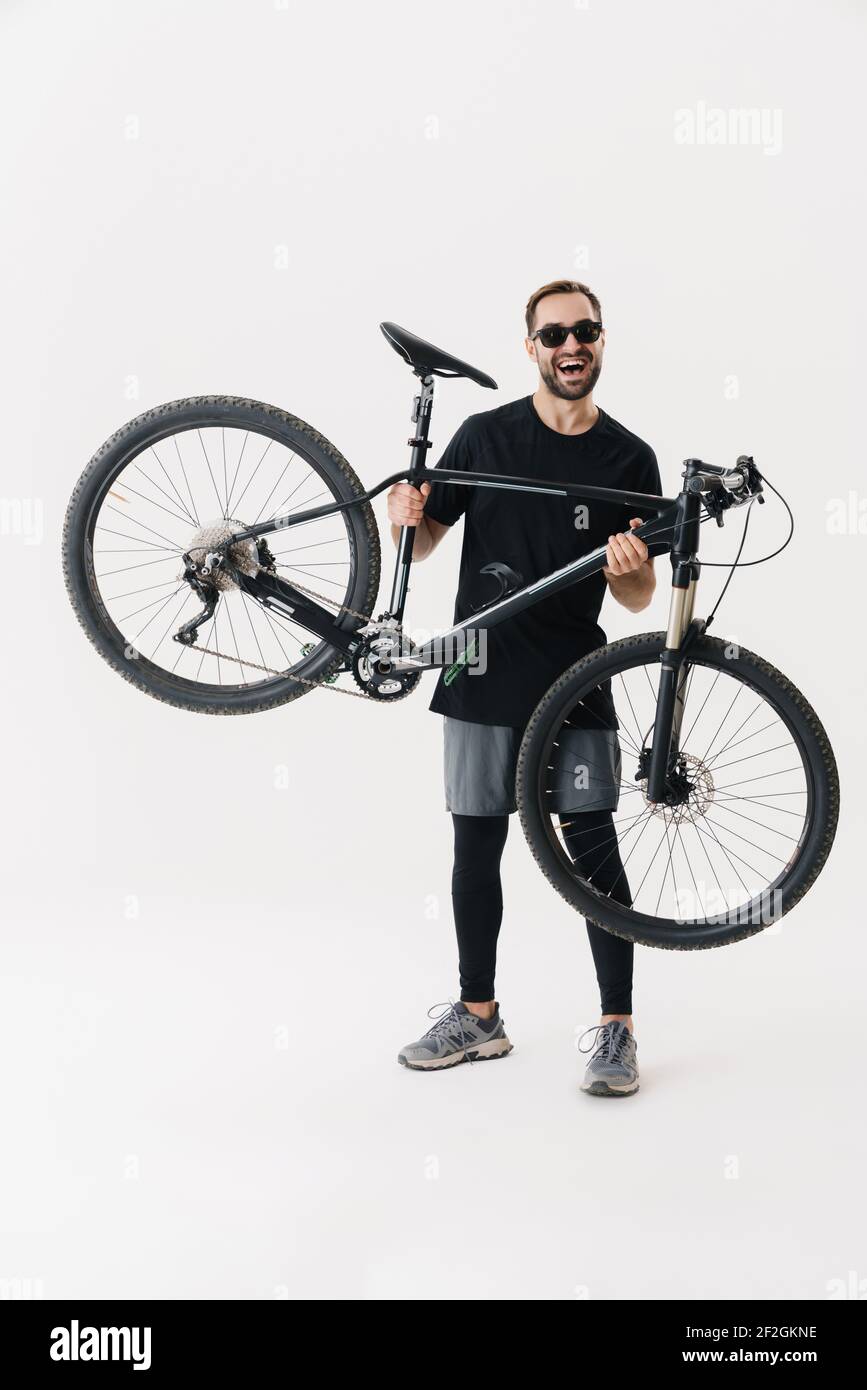 Excited young rider man smiling while posing with his bicycle isolated ...