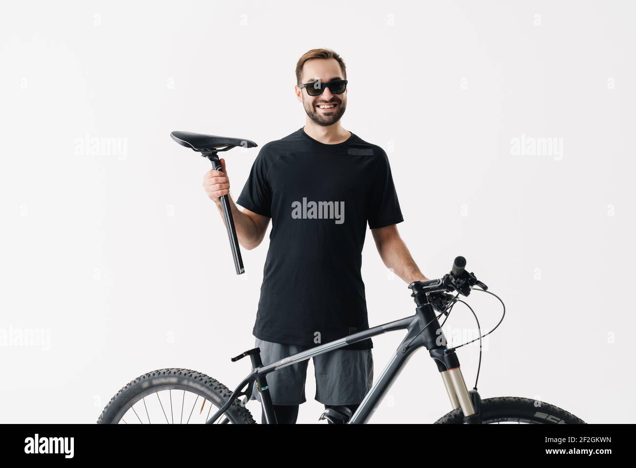 Happy young rider man smiling while posing with his bicycle and saddle ...