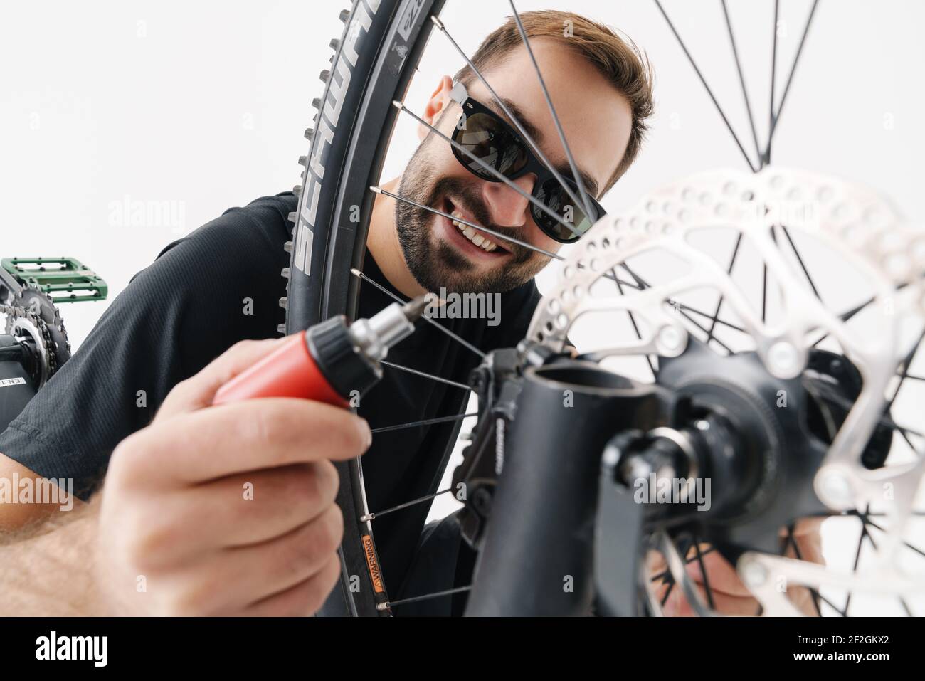 Happy young rider man smiling while repairing his bicycle isolated over ...