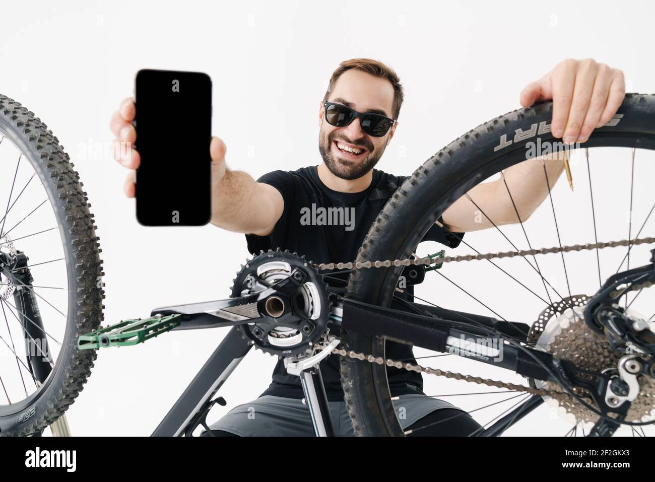 Happy rider man showing cellphone while posing with his bicycle ...