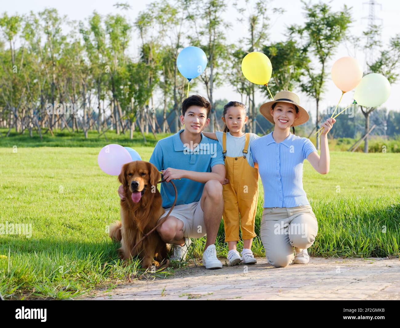 Happy family of three and pet dog in the park smiling Stock Photo - Alamy
