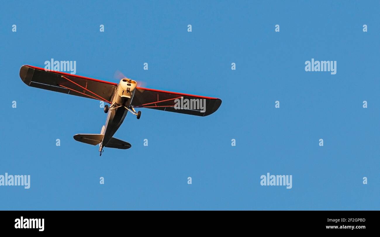 Looking up at small single prop plane with deep blue sky and red wing ...