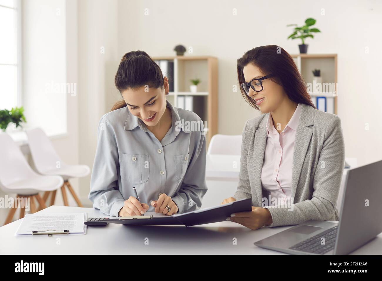 Two business woman signing contract agreement during meeting in office ...