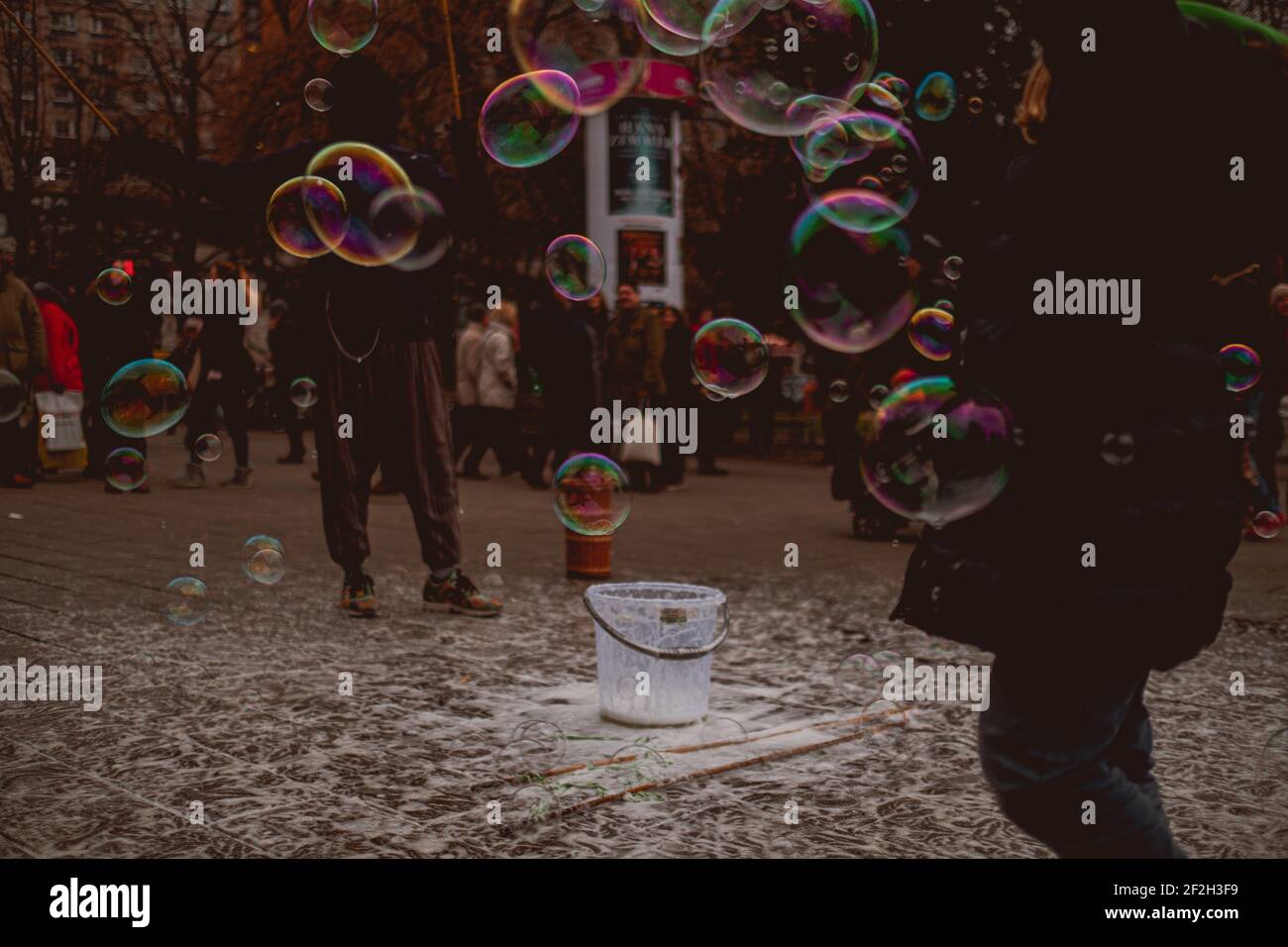 A small crowd gathered around a bucket with soap bubbles outdoors Stock ...