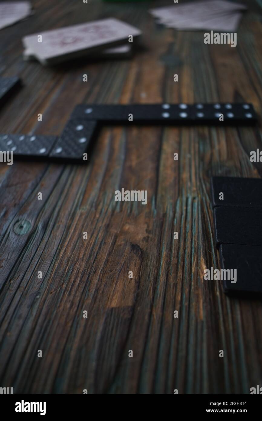 A vertical shot of domino pieces and playing cards on a wooden table ...