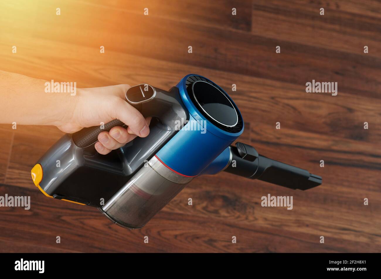 Modern dust cleaner in hand on wooden floor background Stock Photo - Alamy