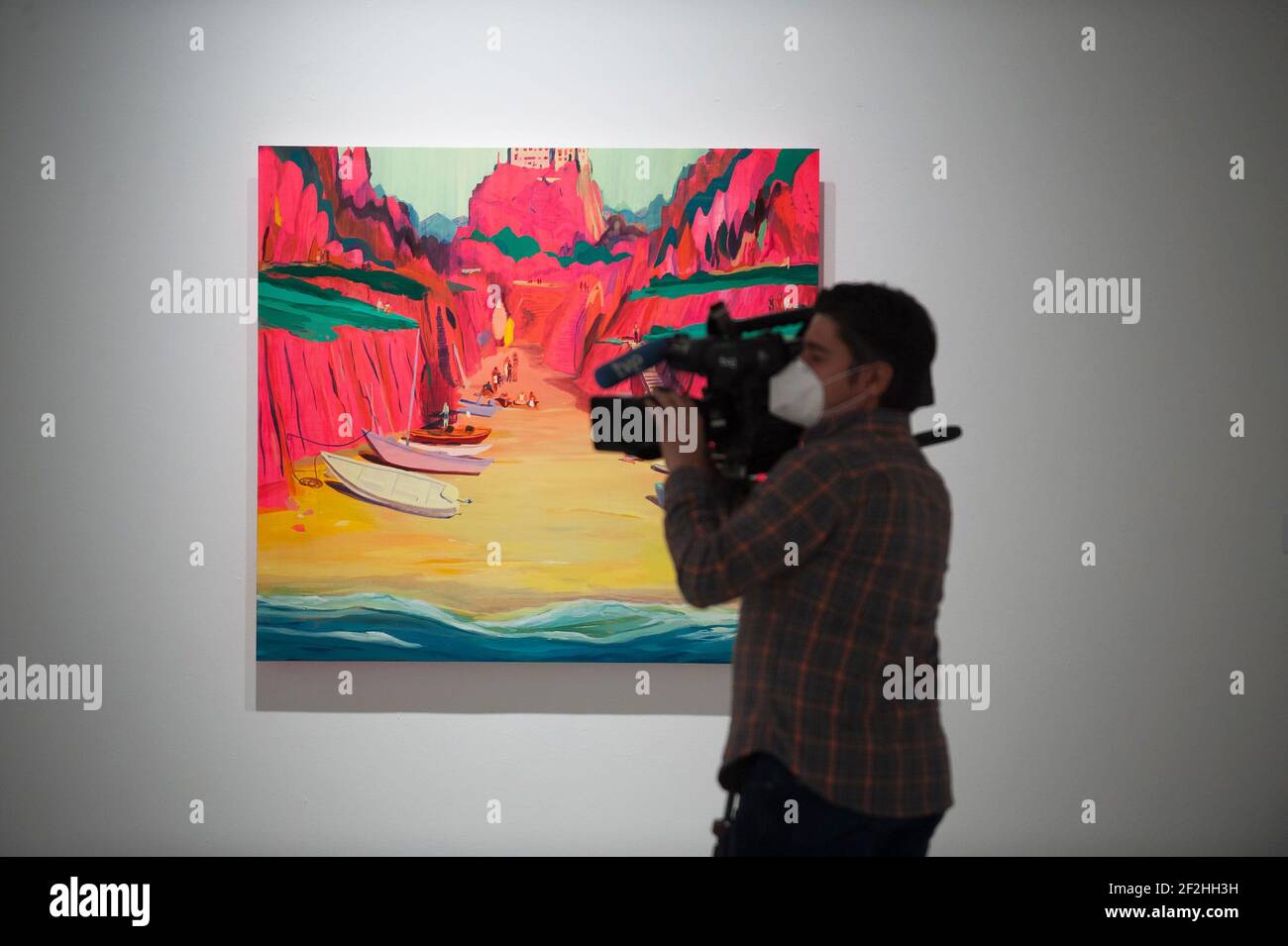 A cameraman wearing a face mask takes a video while standing in front ...