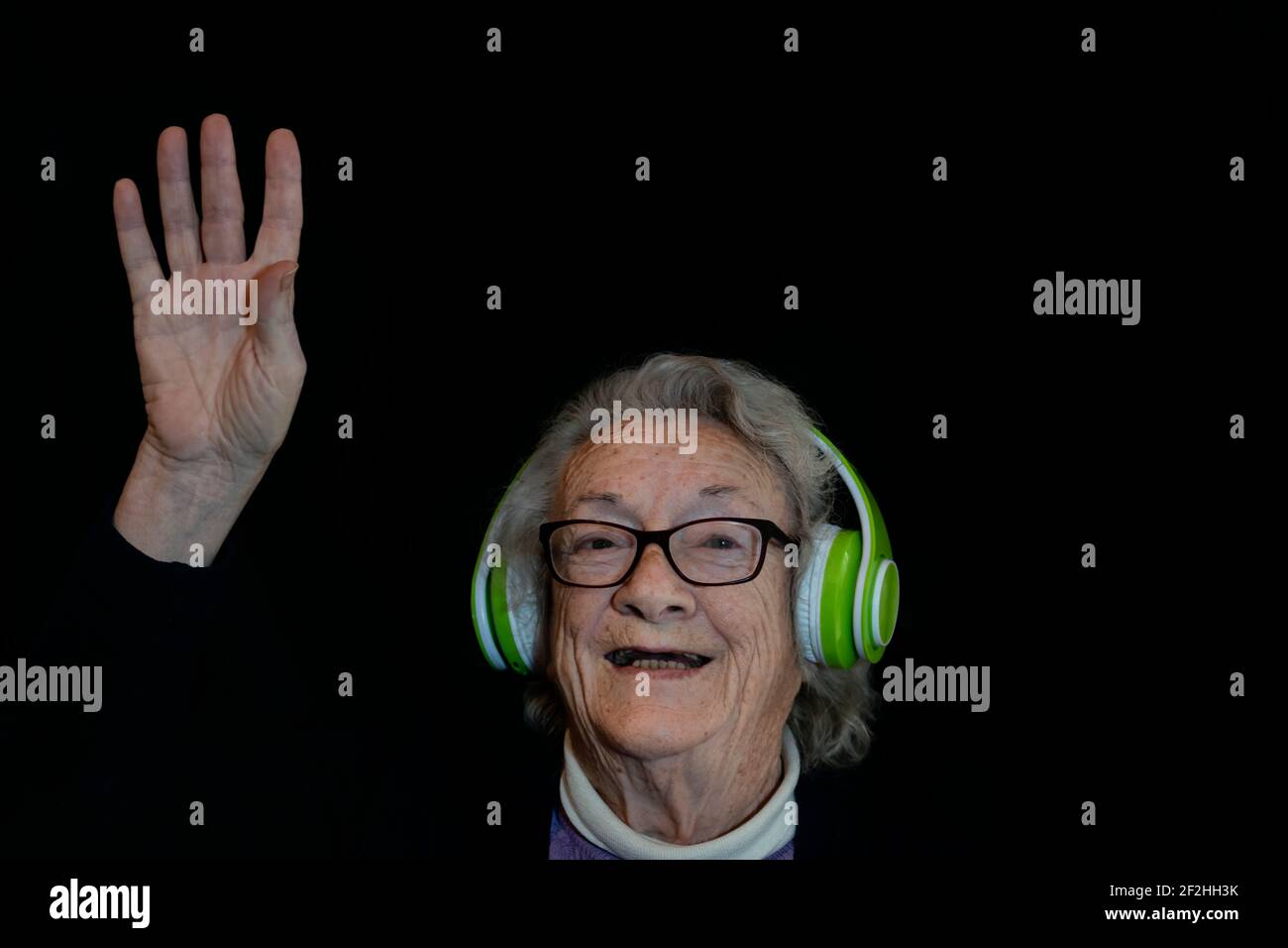 Portrait happy elderly 80s woman raising hand up listening music with ...