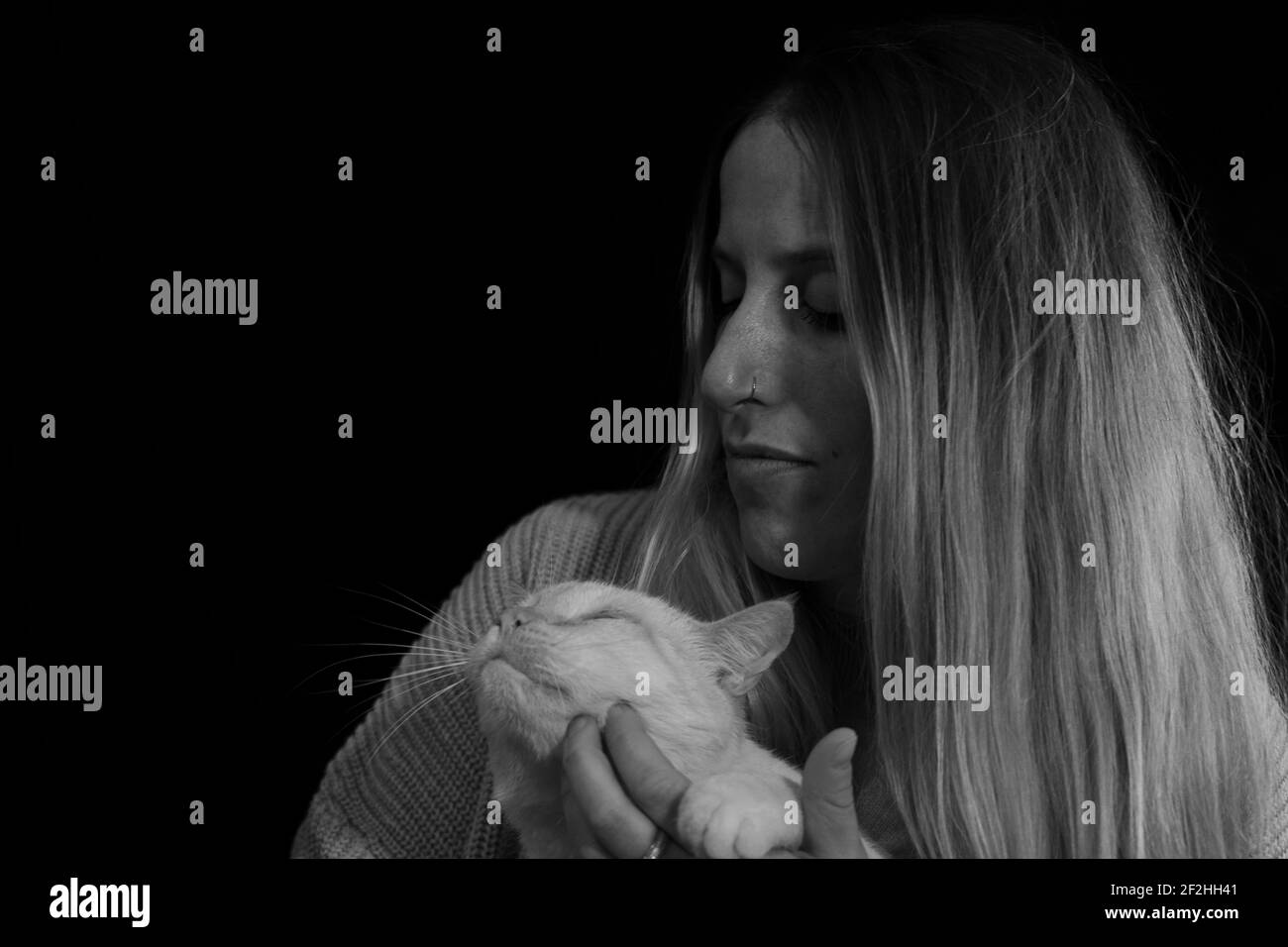 Young beautiful woman hugging cat in dark background.Black and white ...