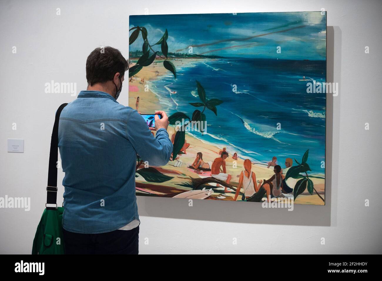 A journalist takes a photo of a painting during the opening of the ...
