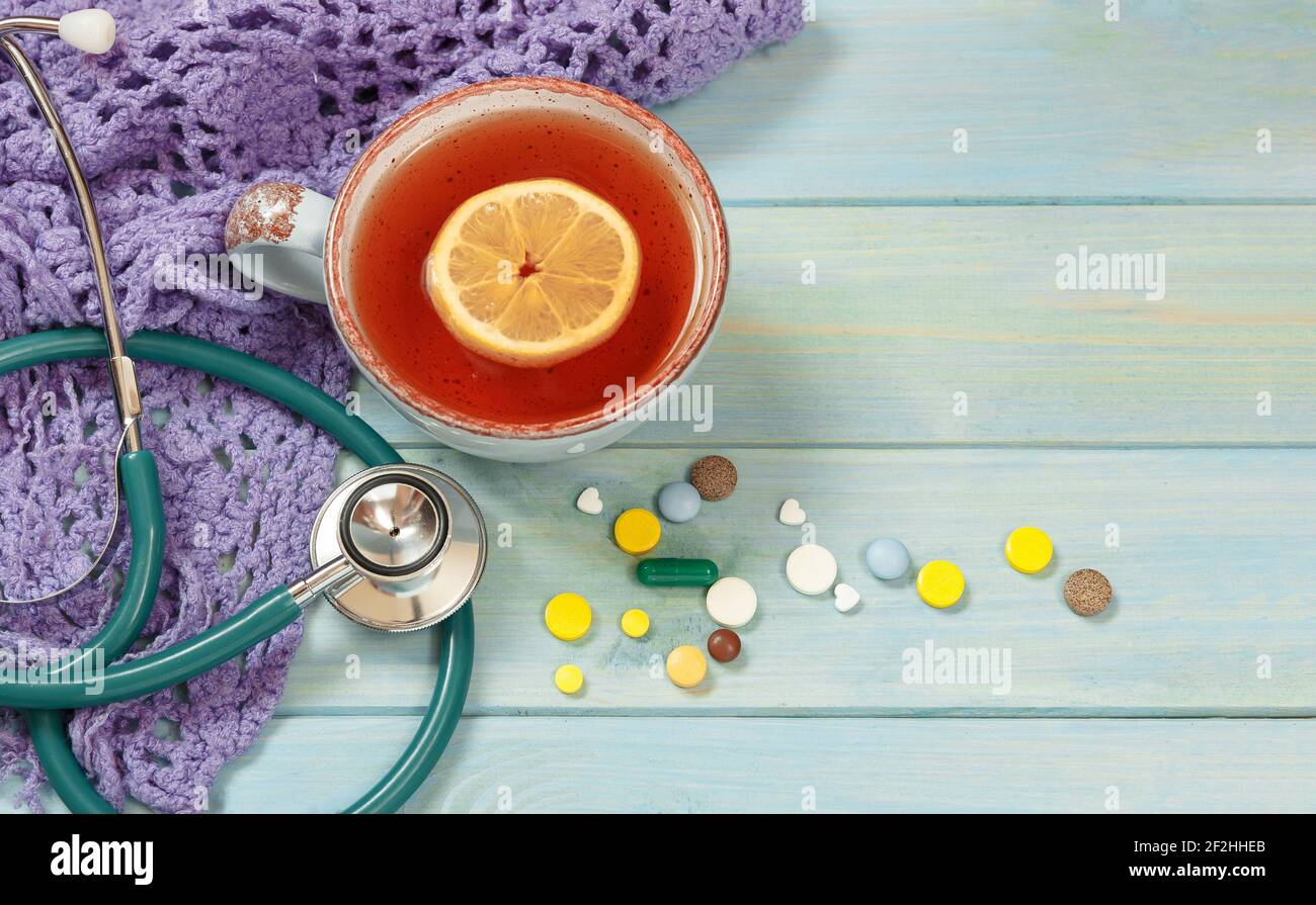 Hot tea, pills, knitted scarf and stethoscope. Cold season Stock Photo ...