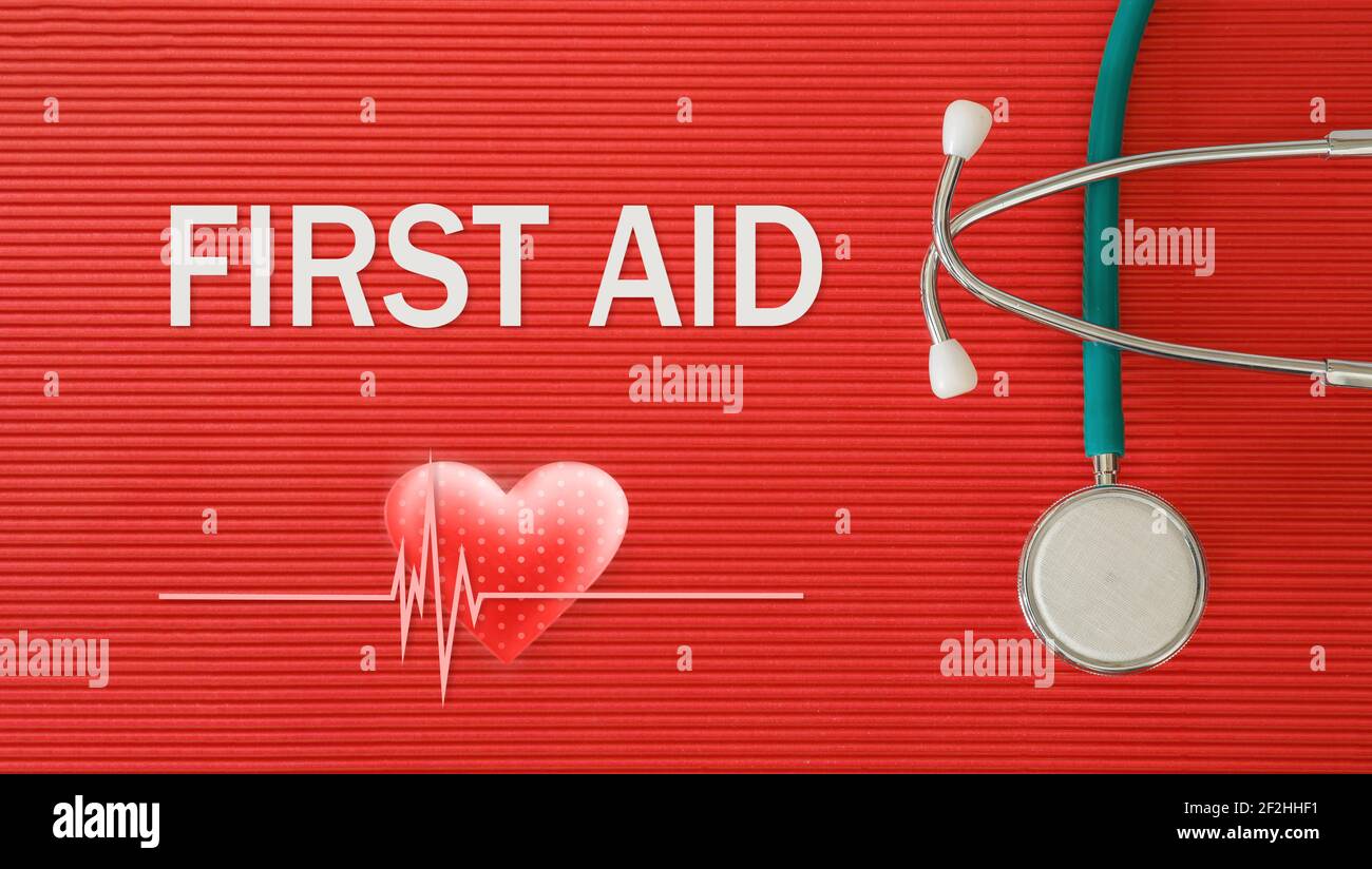 FIRST AID concept with stethoscope and heart shape on a red background ...