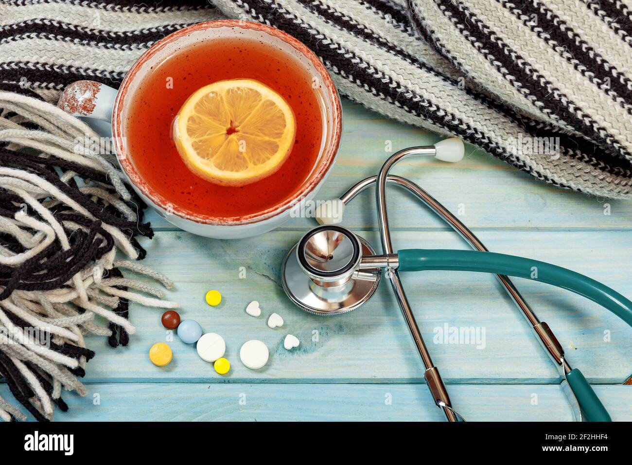 Hot tea, pills, knitted scarf and stethoscope. Cold season Stock Photo ...