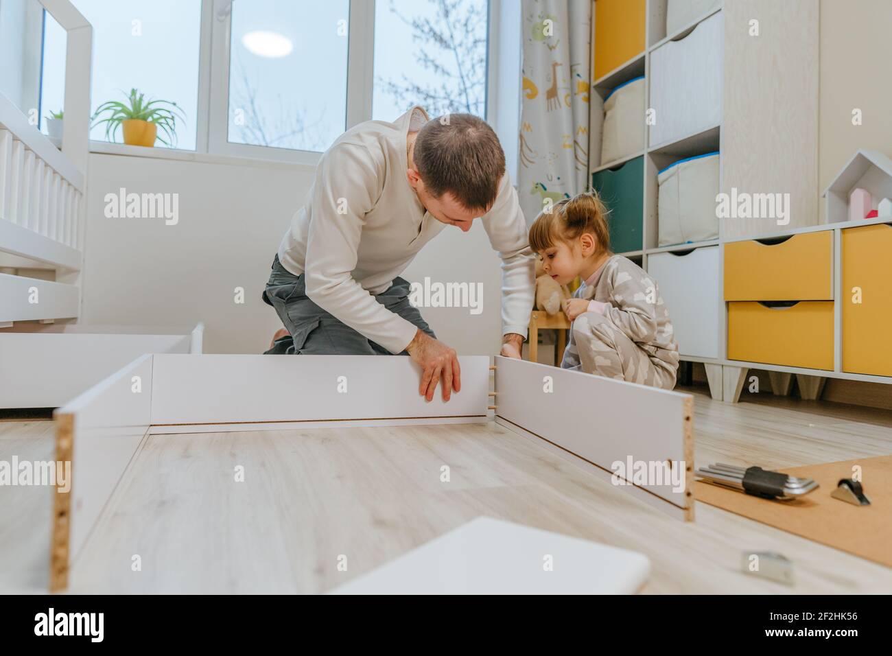 Little 4-years girl helps her father assemble or fixing the drawer of ...