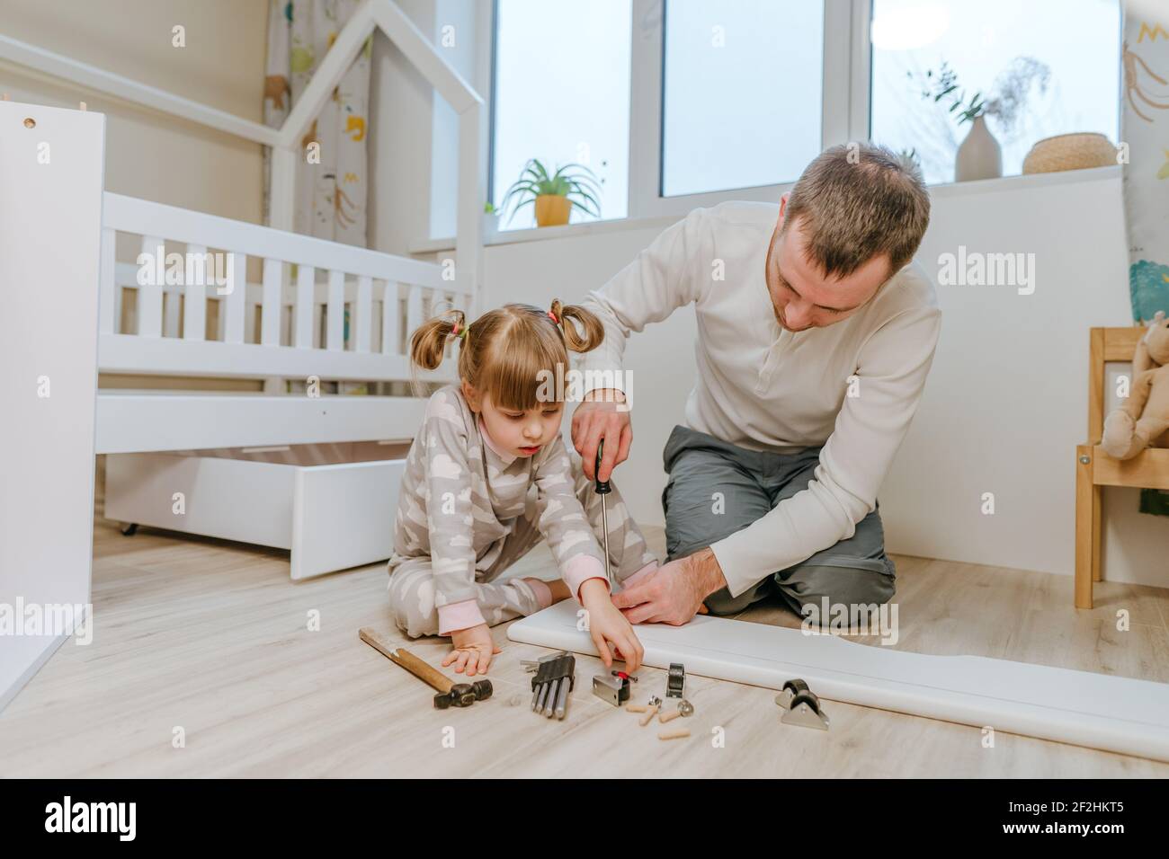 Little 4-years girl helps her father assemble or fixing the drawer of ...