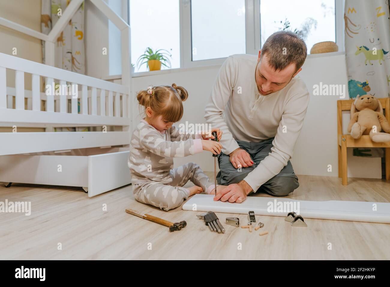 Little 4-years girl helps her father assemble or fixing the drawer of ...