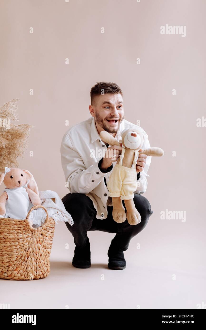 Cheerful positive man with beard in white shirt holding teddy bear ...