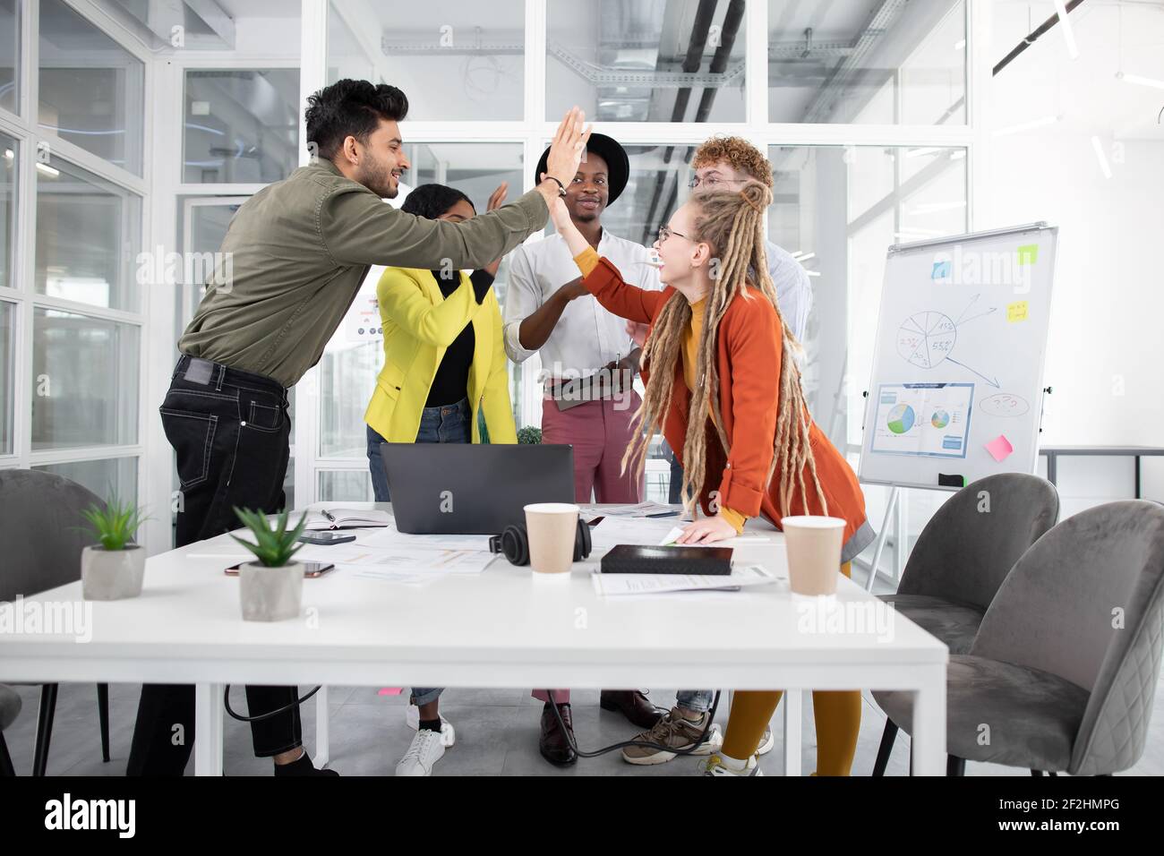 Mixed race people giving high five after successful meeting in modern ...