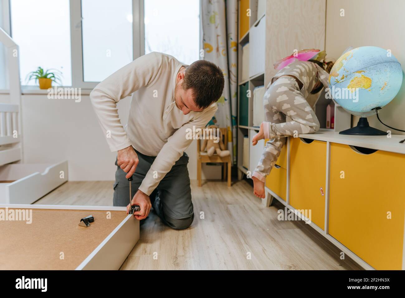 Little 4-years girl helps her father assemble or fixing the drawer of ...