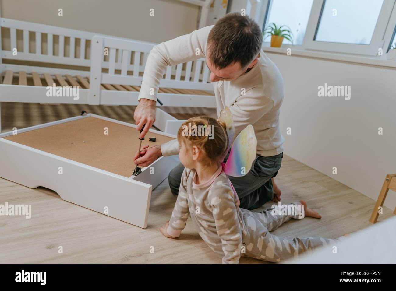 Little 4-years girl helps her father assemble or fixing the drawer of ...