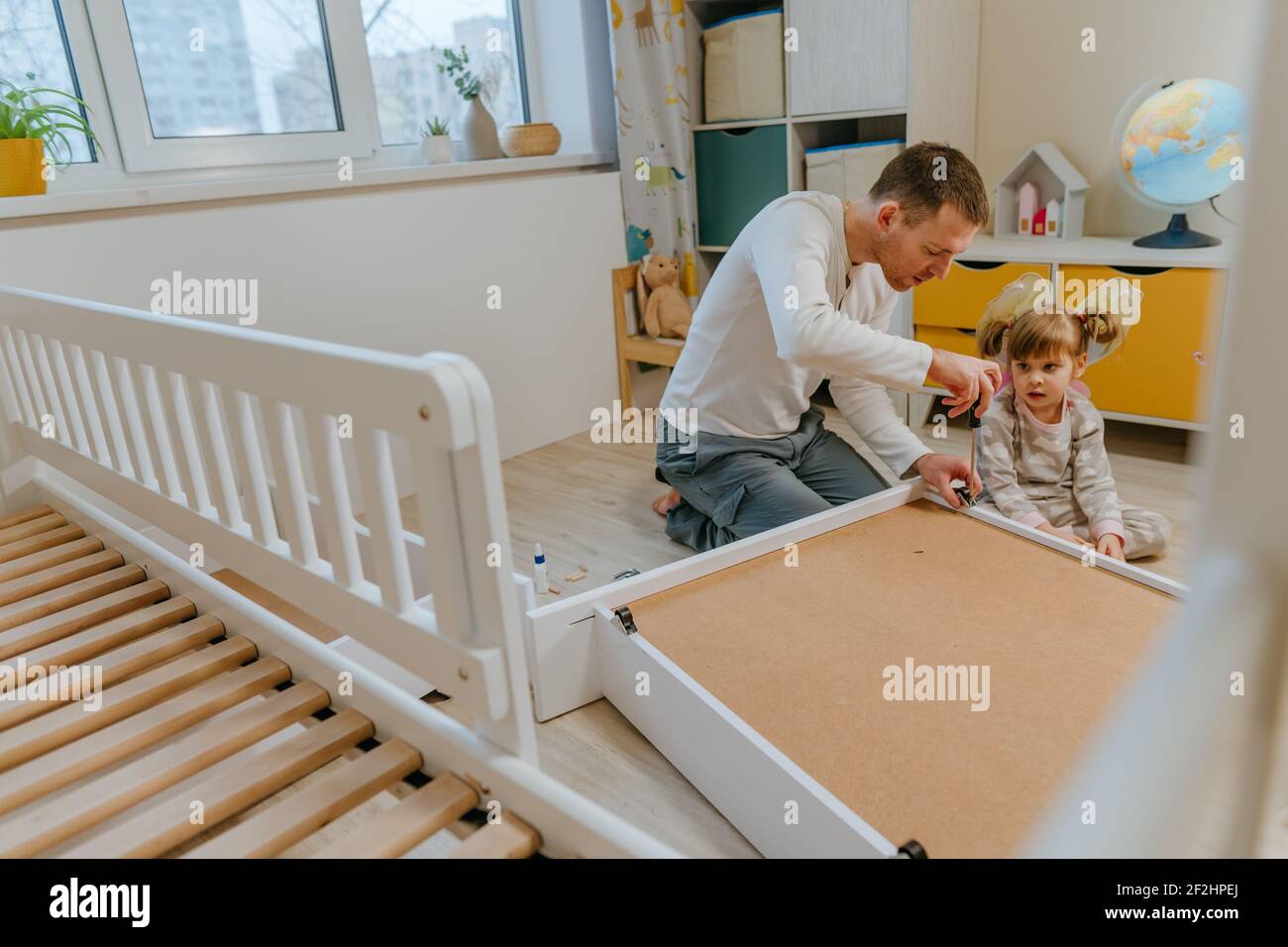Little 4-years girl helps her father assemble or fixing the drawer of ...