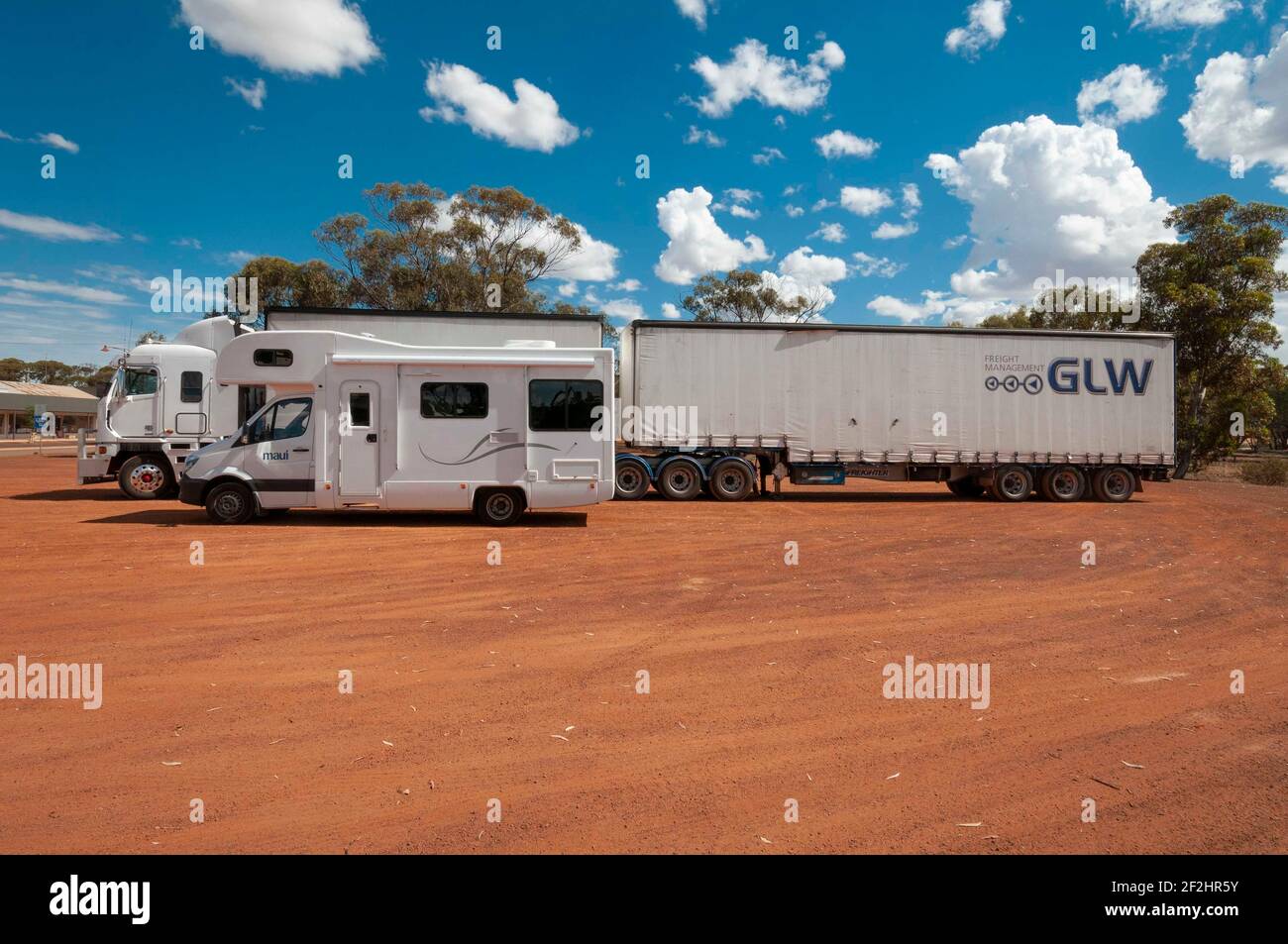 Tourist motorhome parked beside road train in a red earth car park in ...