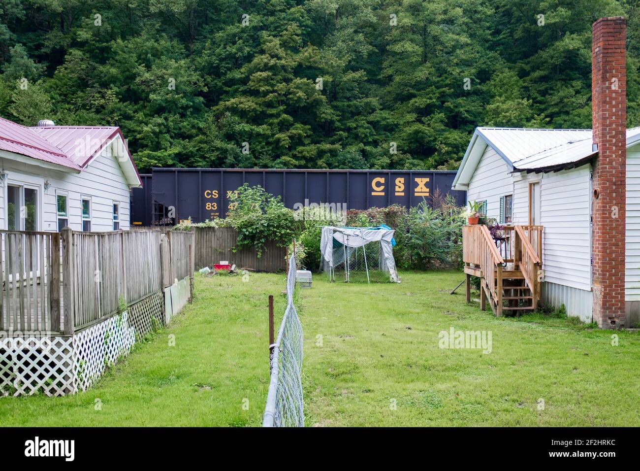 A CSX coal hopper train car behind yards of poor houses. In Clinchfield ...