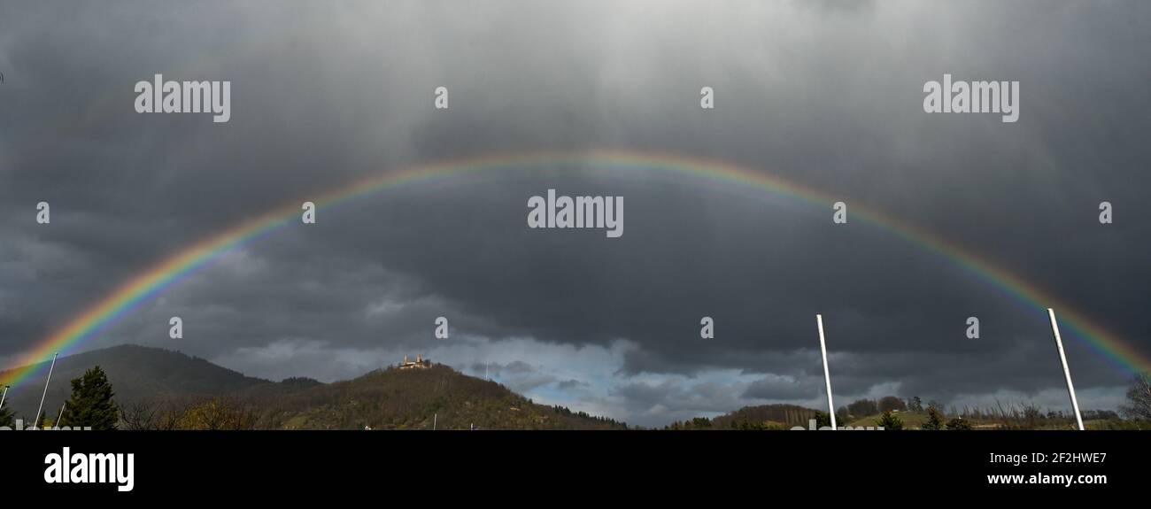 Bensheim, Germany. 12th Mar, 2021. A rainbow can be seen in the dark sky above Auerbach Castle ...