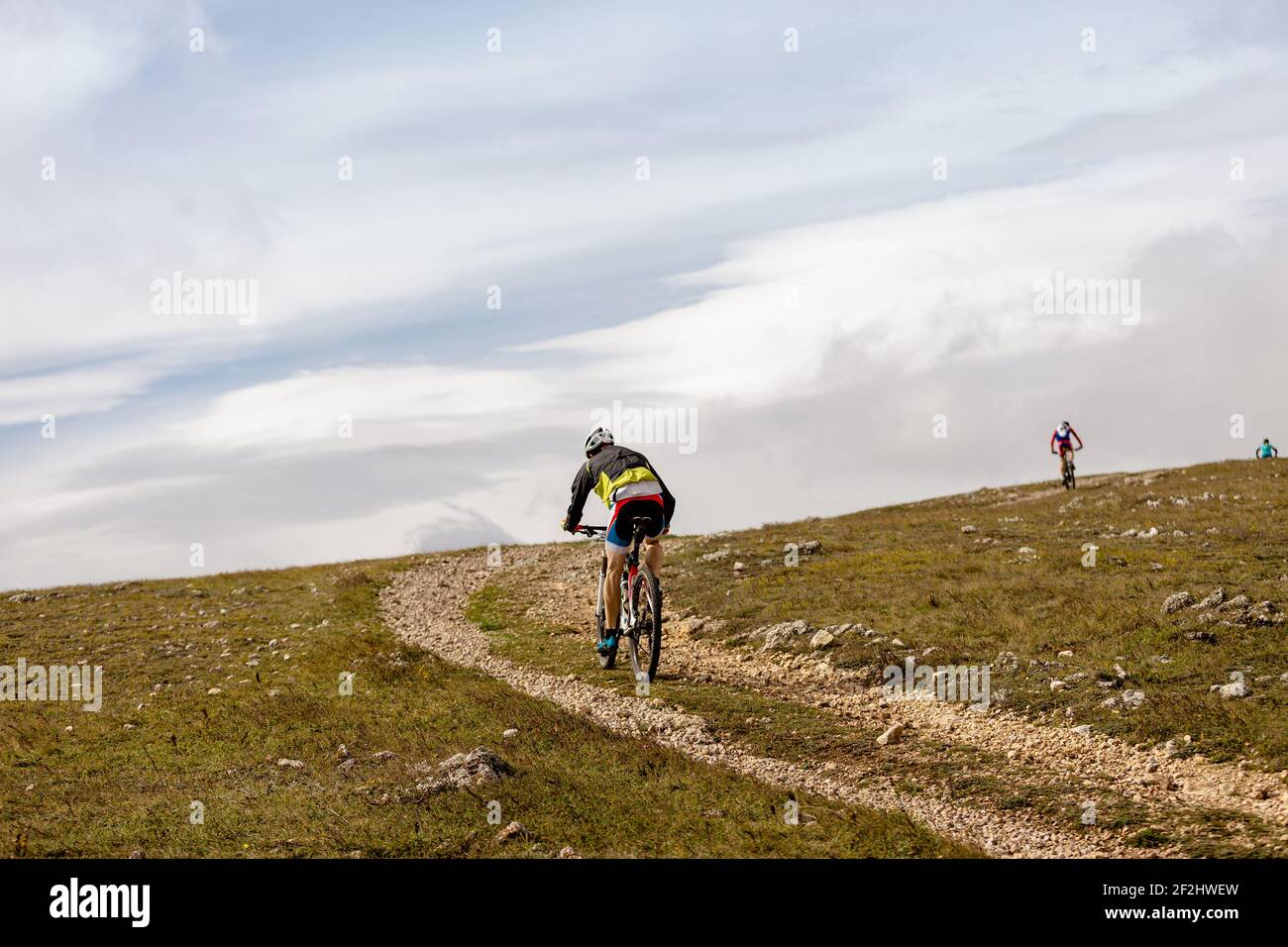 male cyclists riding uphill on mountain road on mountain bike Stock ...