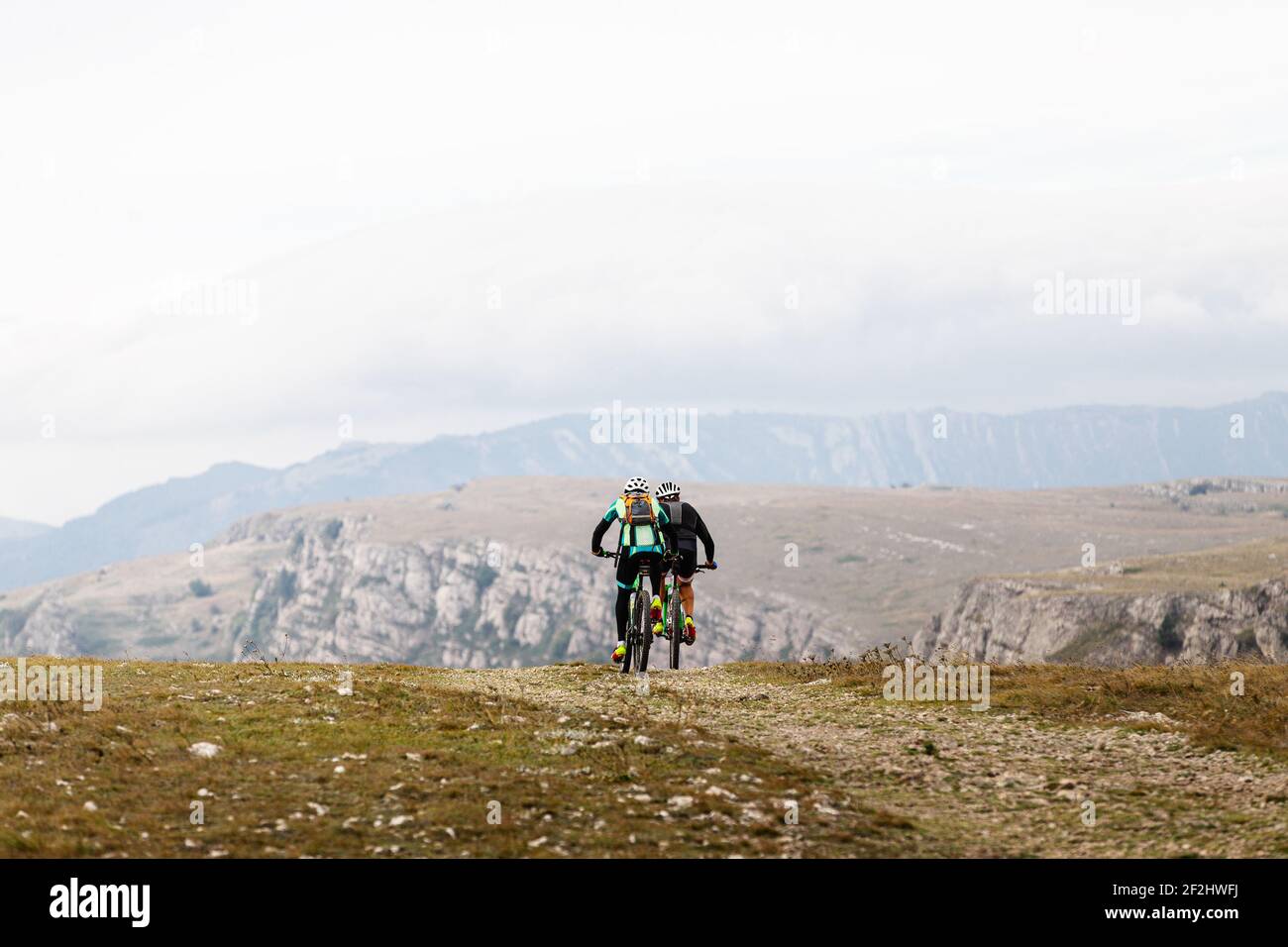 back two cyclists riding on mountain road on mountain bike Stock Photo ...