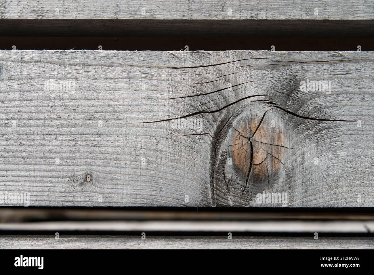 Faded, parallel wooden slats with knotholes and cracks against a black ...