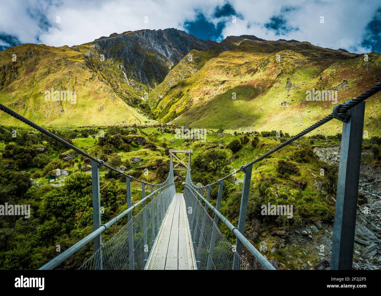 Long suspension bridge on way to green mountains, New Zealand. Walkway ...