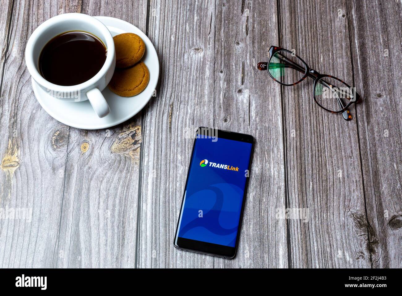 A Mobile phone or cell phone laid on a wooden table with the Translink ...