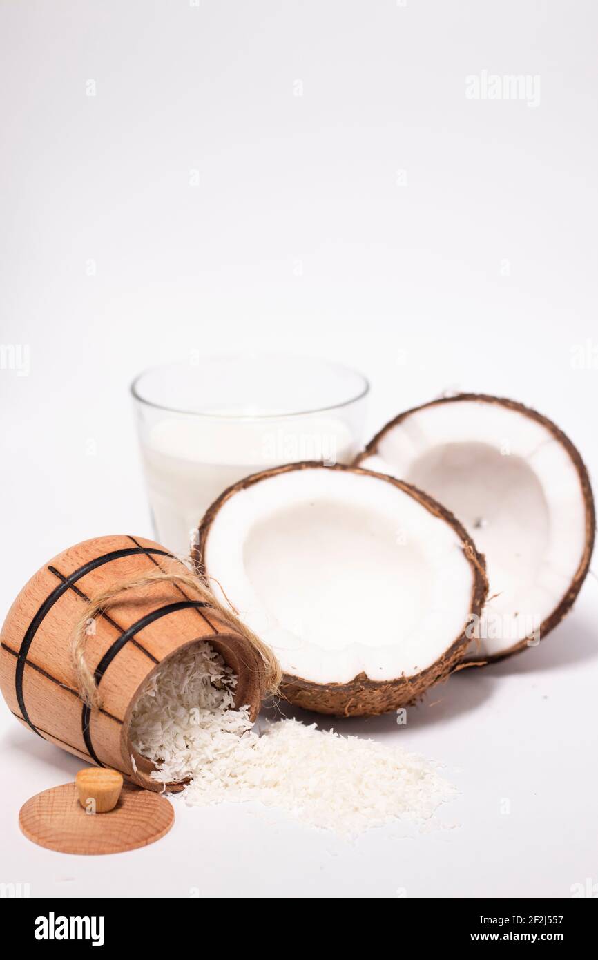 opened coconut near coconut flakes in wooden bowl and glass of coconut ...