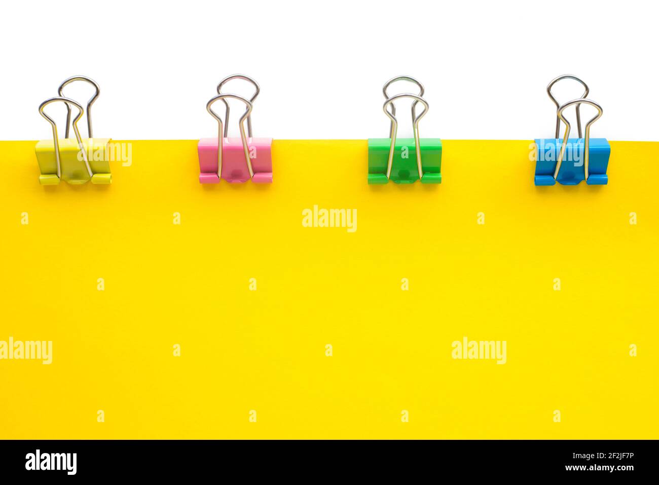 Blank yellow paper with colored small paper clips attached around it ...