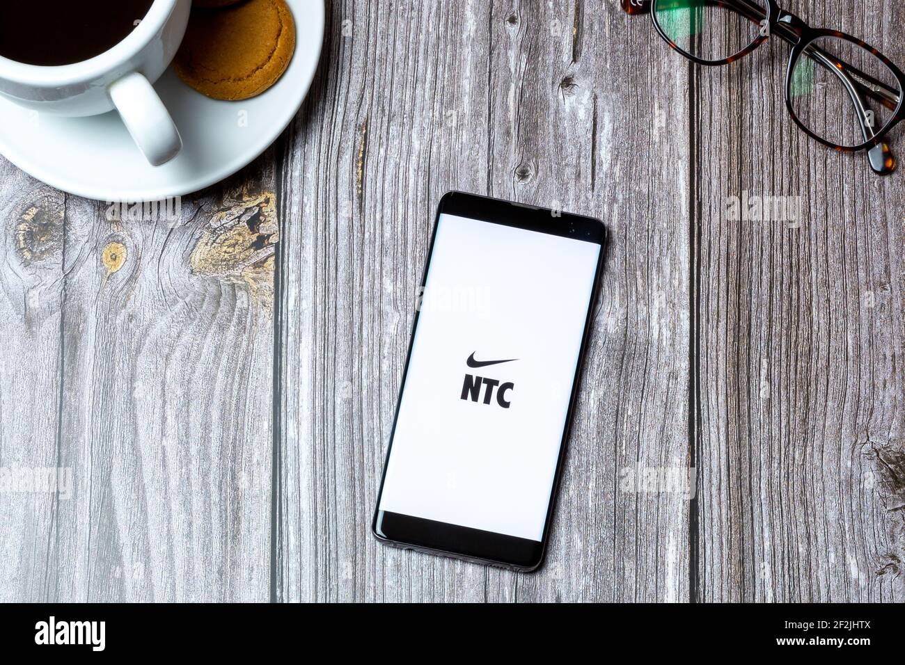 A Mobile phone or cell phone laid on a wooden table with the NIKE NTC ...