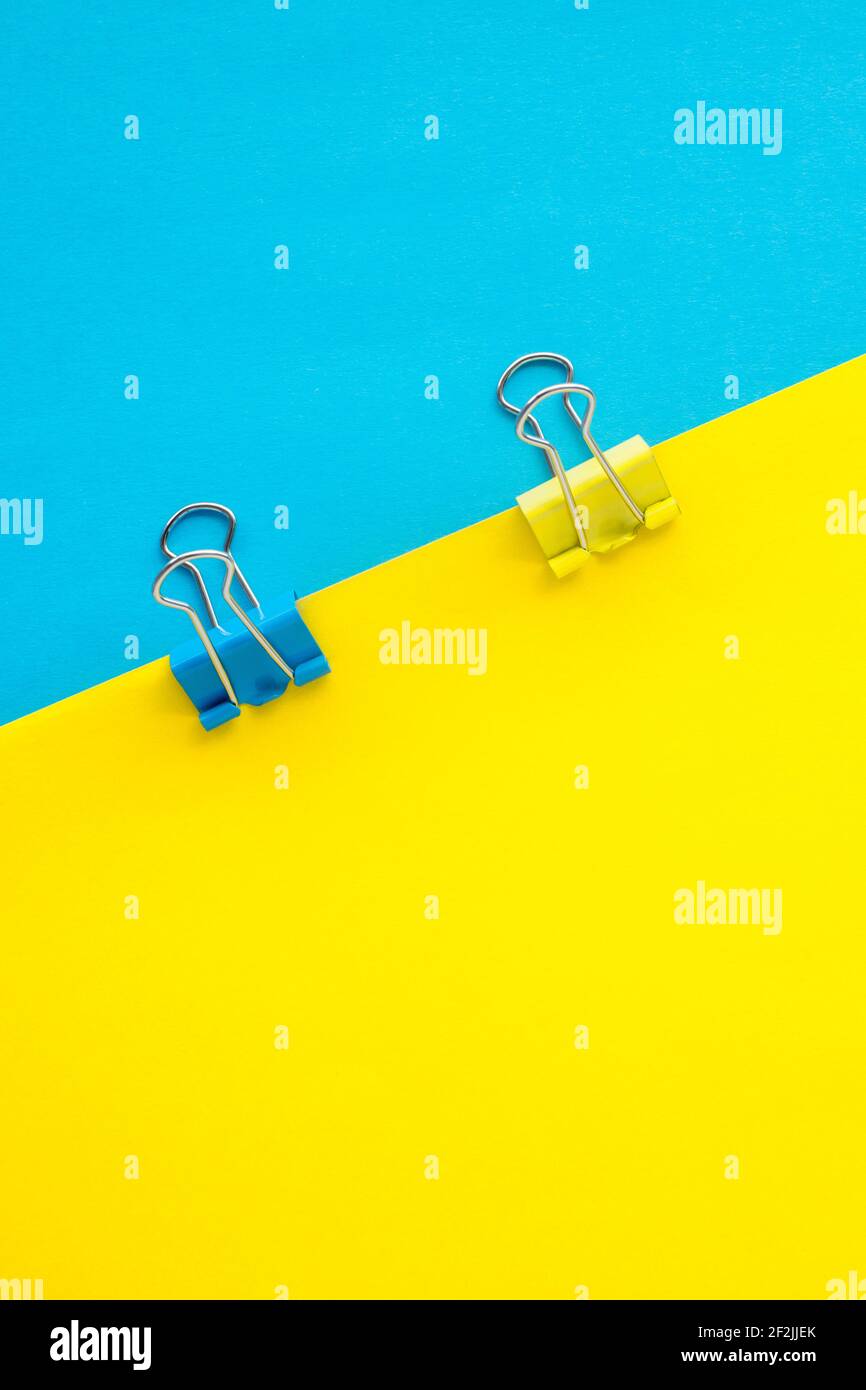 Binder clips on a blue and yellow paper background Stock Photo - Alamy