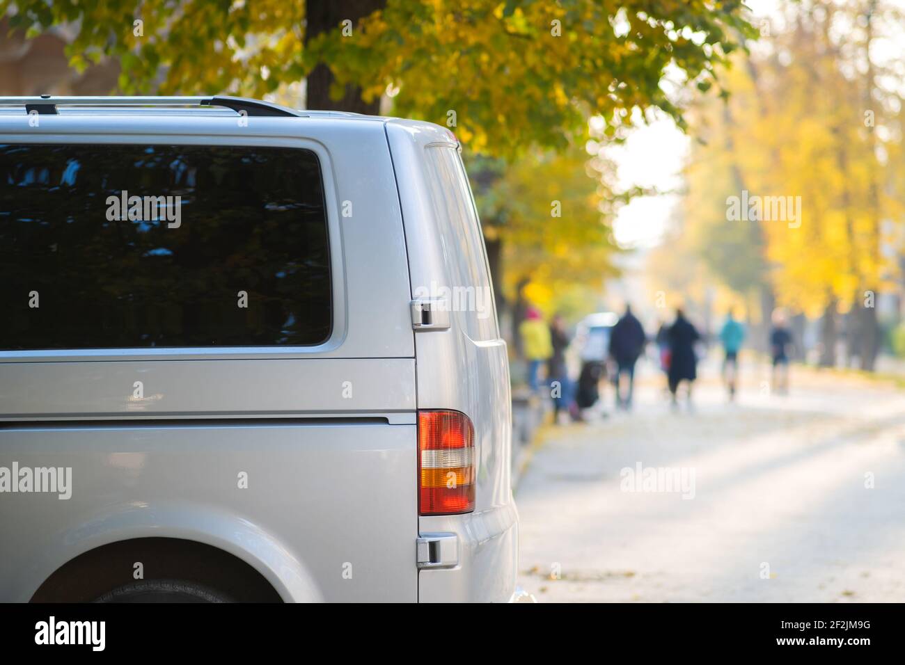 Van parked on a city street side on bright autumn day with blurred ...