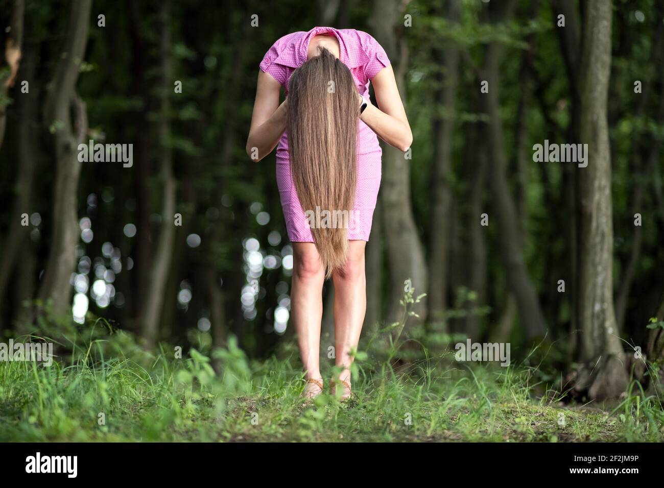 Creepy woman with long hair leaning bent down in moody dark forest ...