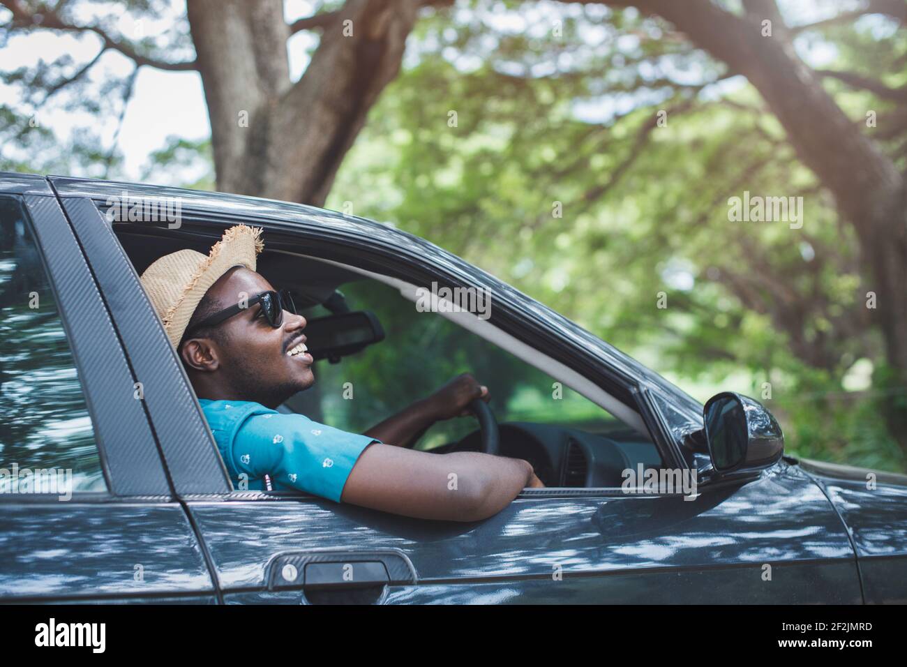 Happy african driver smiling while sitting in a car with open front ...