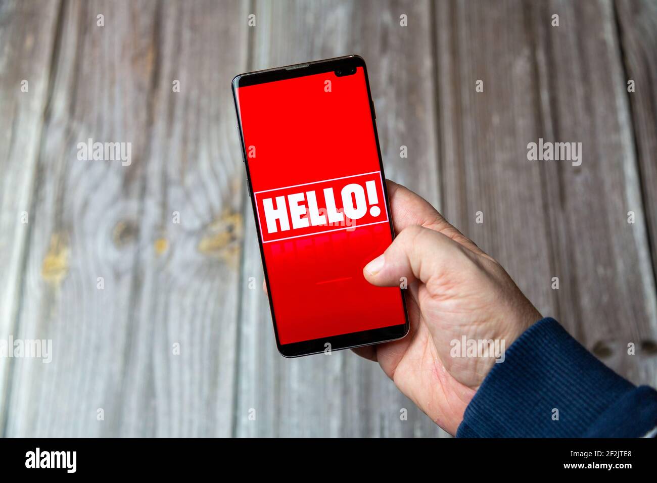 A Mobile phone or cell phone being held in a hand with the Hello ...