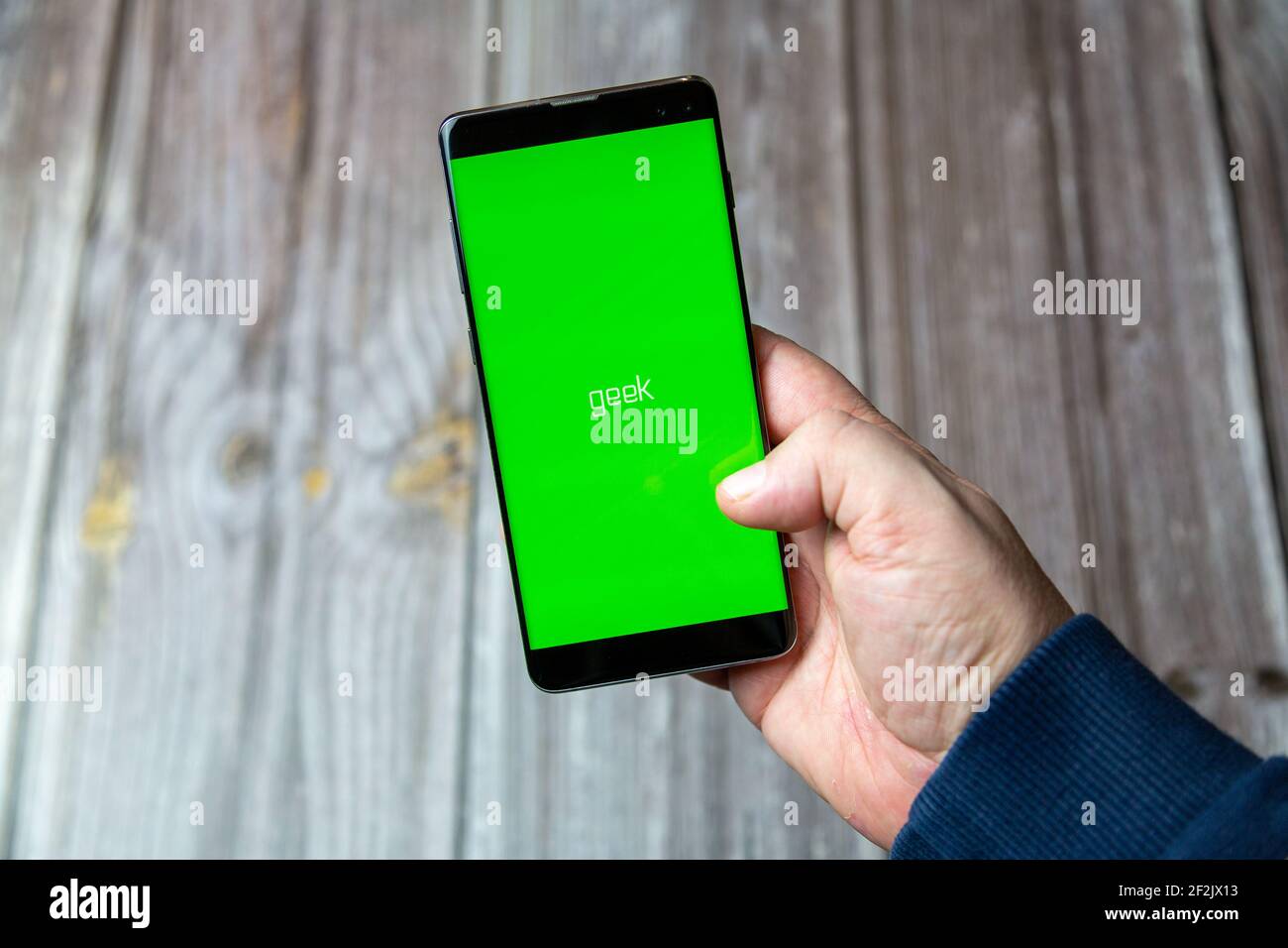 A Mobile phone or cell phone being held in a hand with the Geek app ...