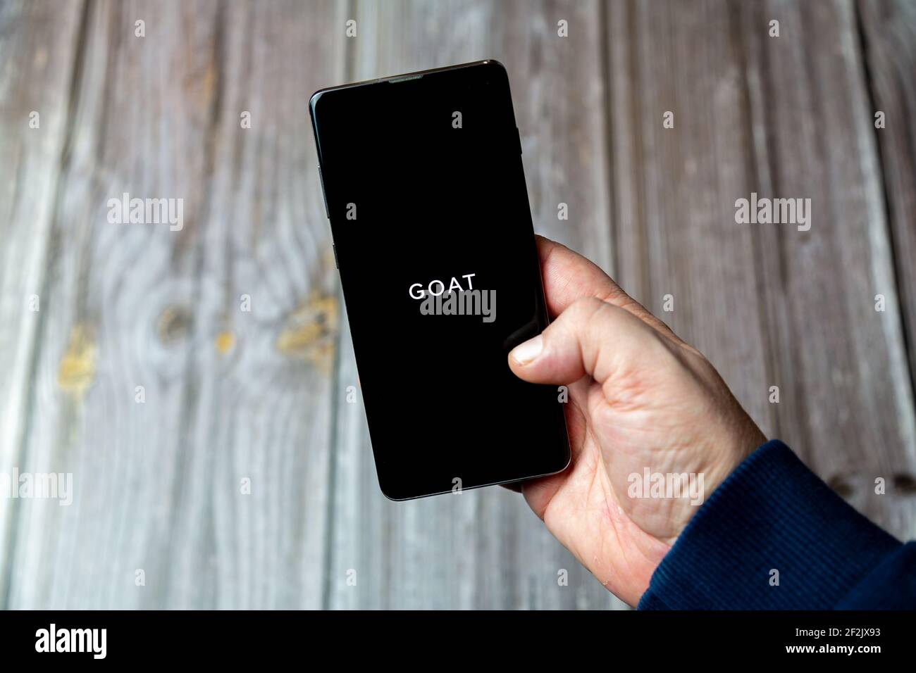 A Mobile phone or cell phone being held in a hand with the GOAT app ...