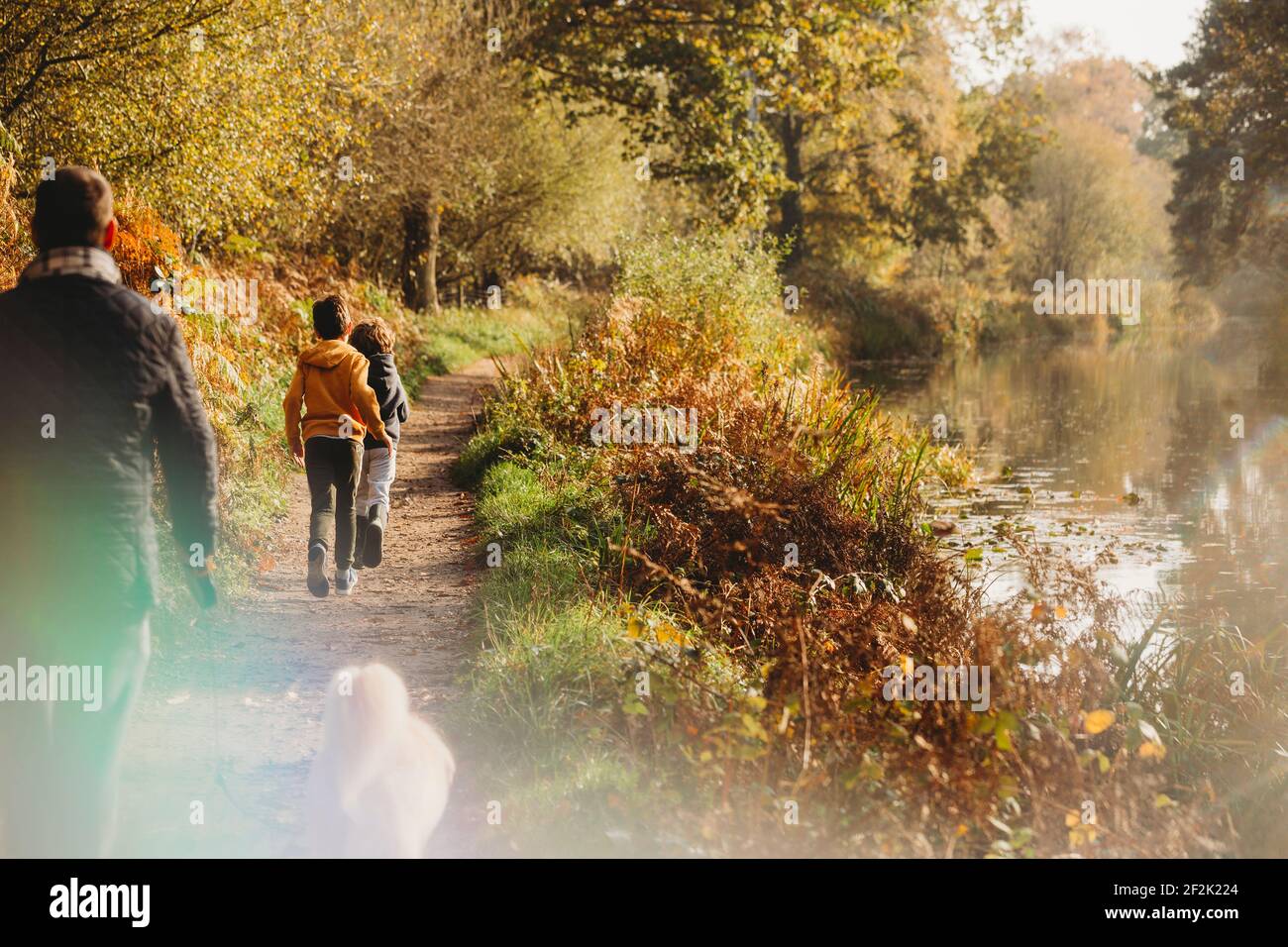 Family walking along path by canal in fall Stock Photo - Alamy