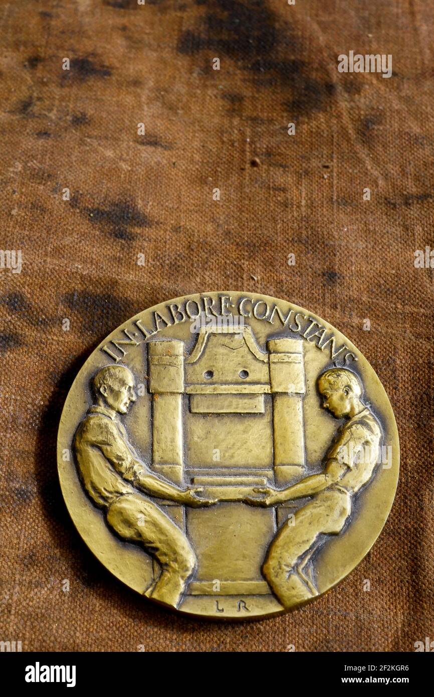 Bronze medal, with two workers and the words "Hard workers ...
